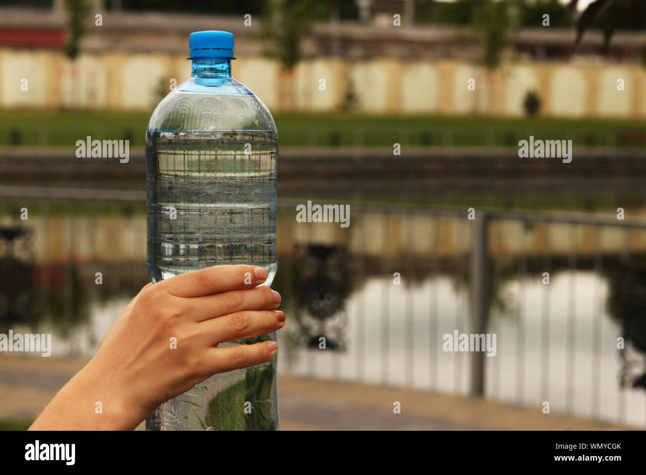 Bottle of mineral water in a female hand in a city park during a ...