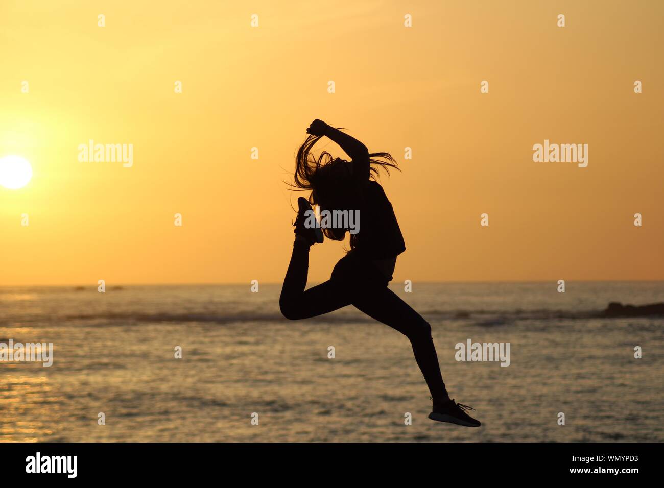 Silhouette of a female jumping in a pose with a blurred background ...