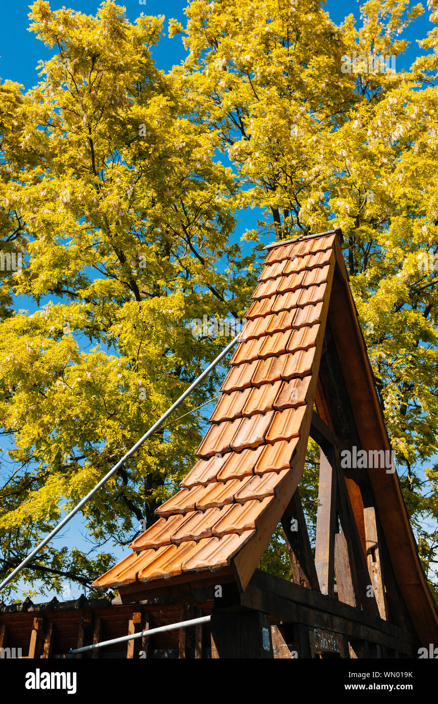 Traditional gate entrance covered with roof tiles and yellow tree in ...