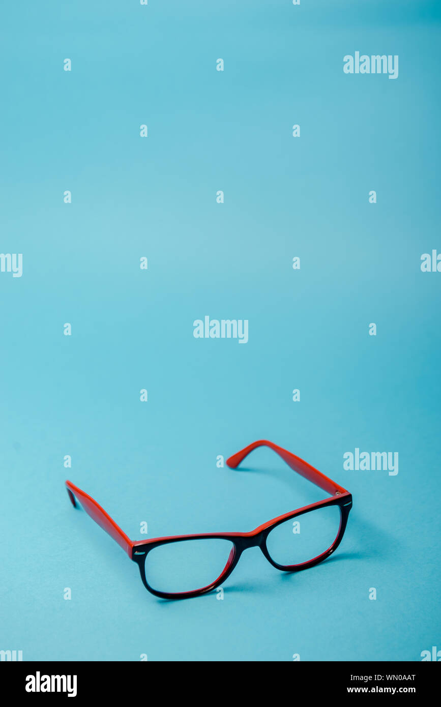 pair of red plastic-rimmed eyeglasses on a blue background Stock Photo ...