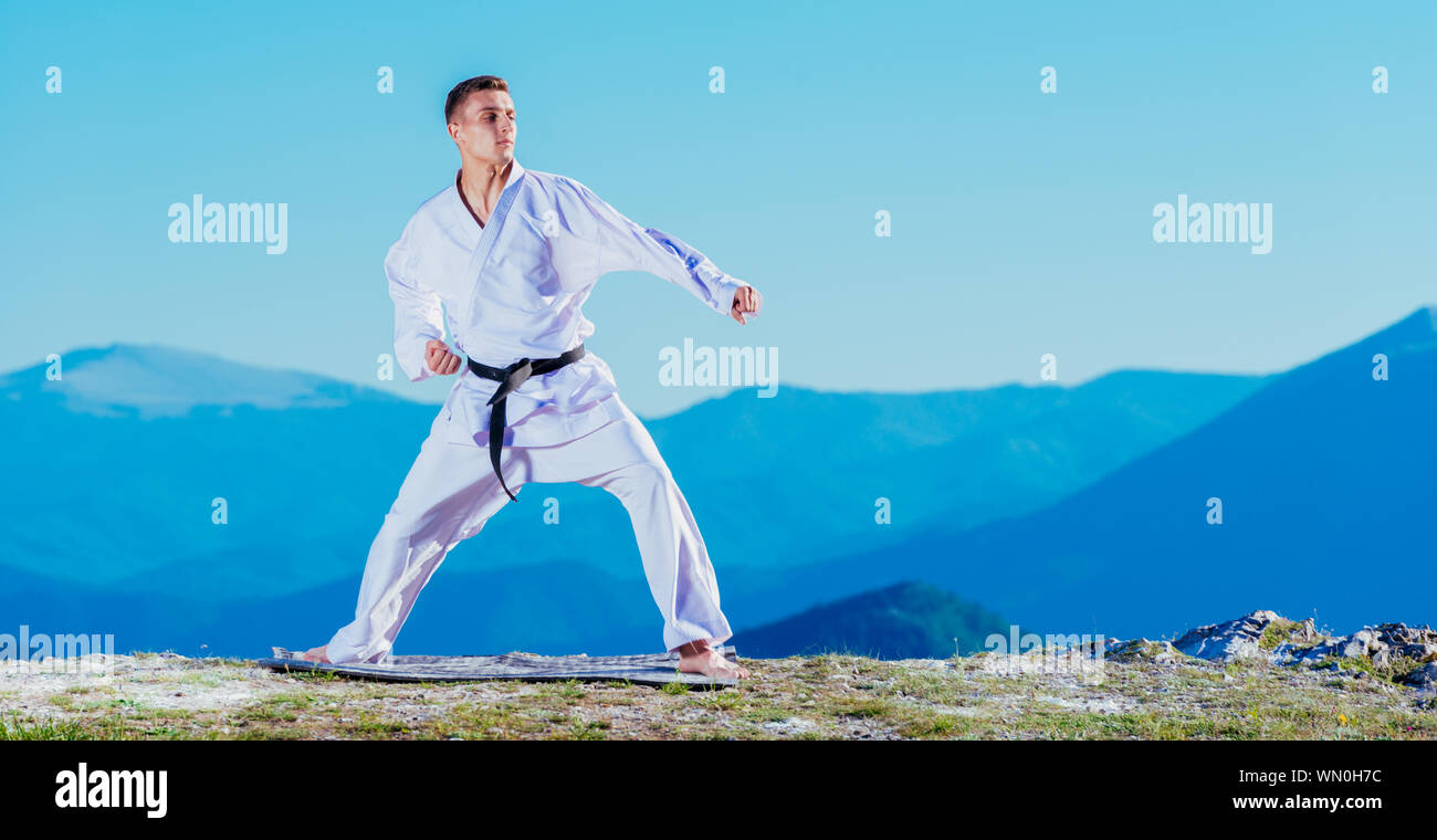 Karate man in a kimono performs a front hand kick (Choku-zuki) while ...