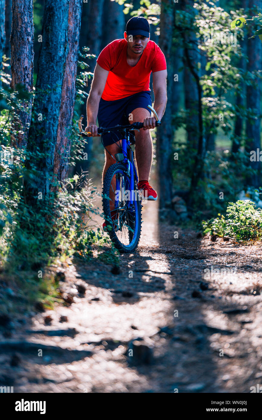 Man on mountain bike rides on the trail through the woods while moving ...