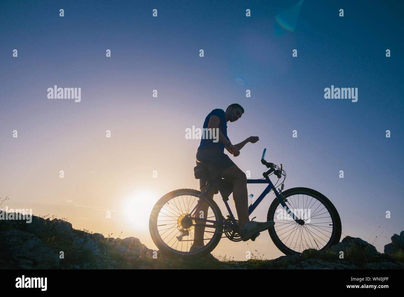 Strong fit male mountain biker performing stunts on rocky terrain on a ...