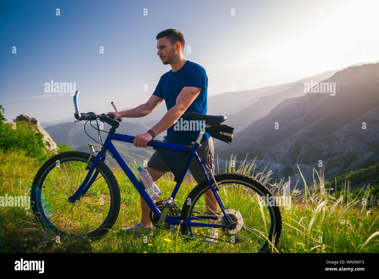 Perspective of a fit mountain biker pushing his bike uphill with ...