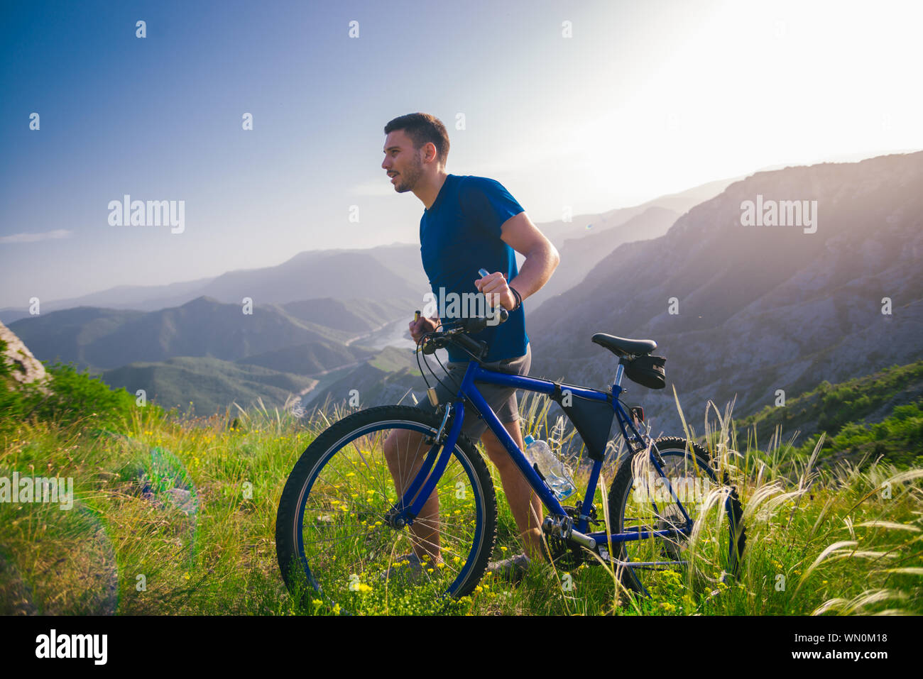 Perspective of a fit mountain biker pushing his bike uphill with ...