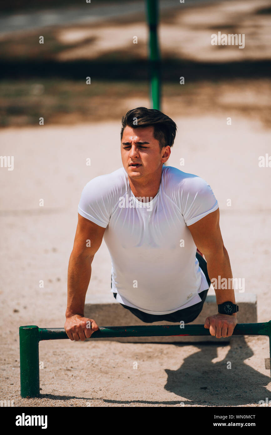 Young fit man doing horizontal push-ups with bars Stock Photo - Alamy