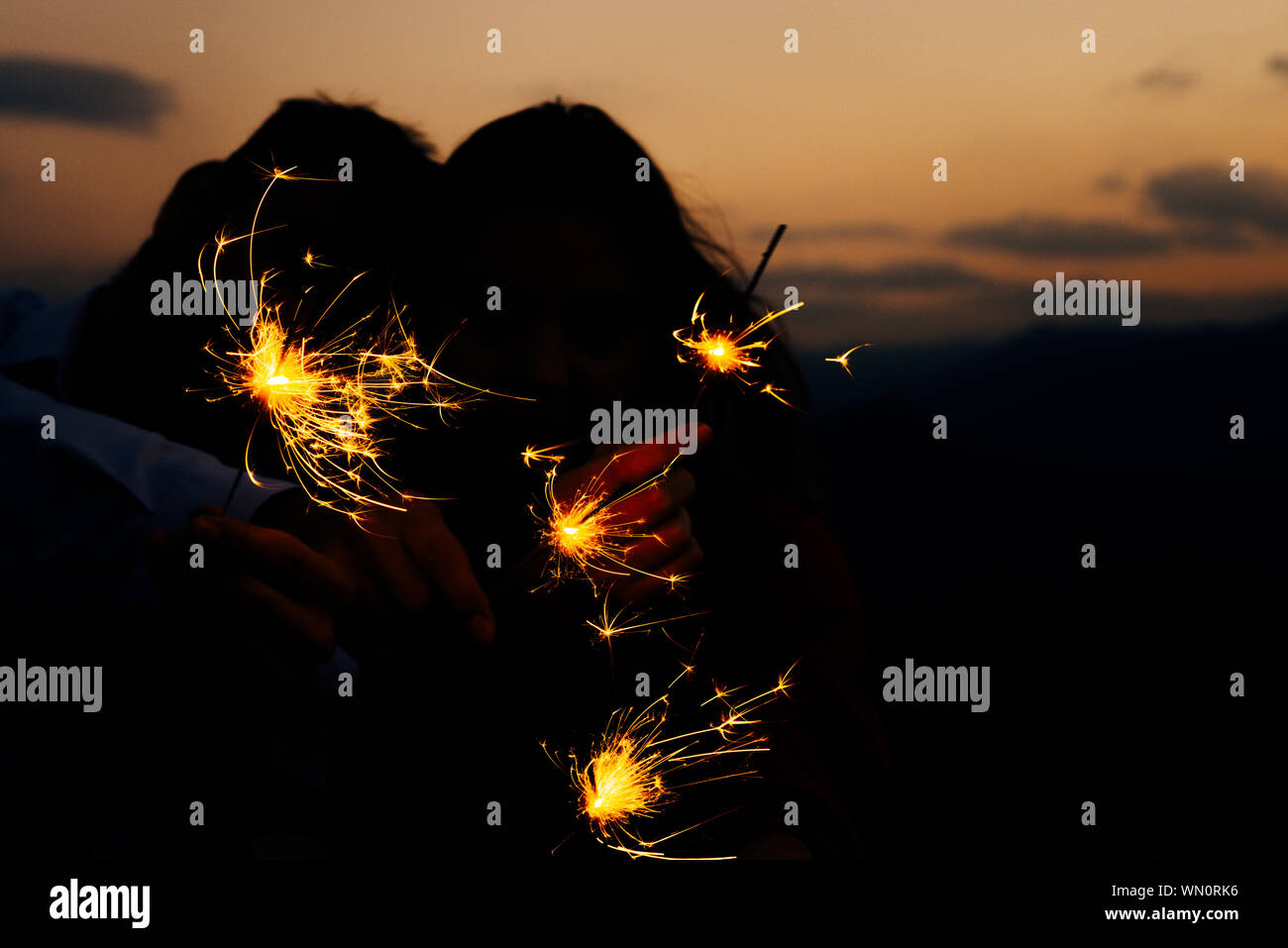 Portrait of young attractive celebrating couple holding firecrackers ...
