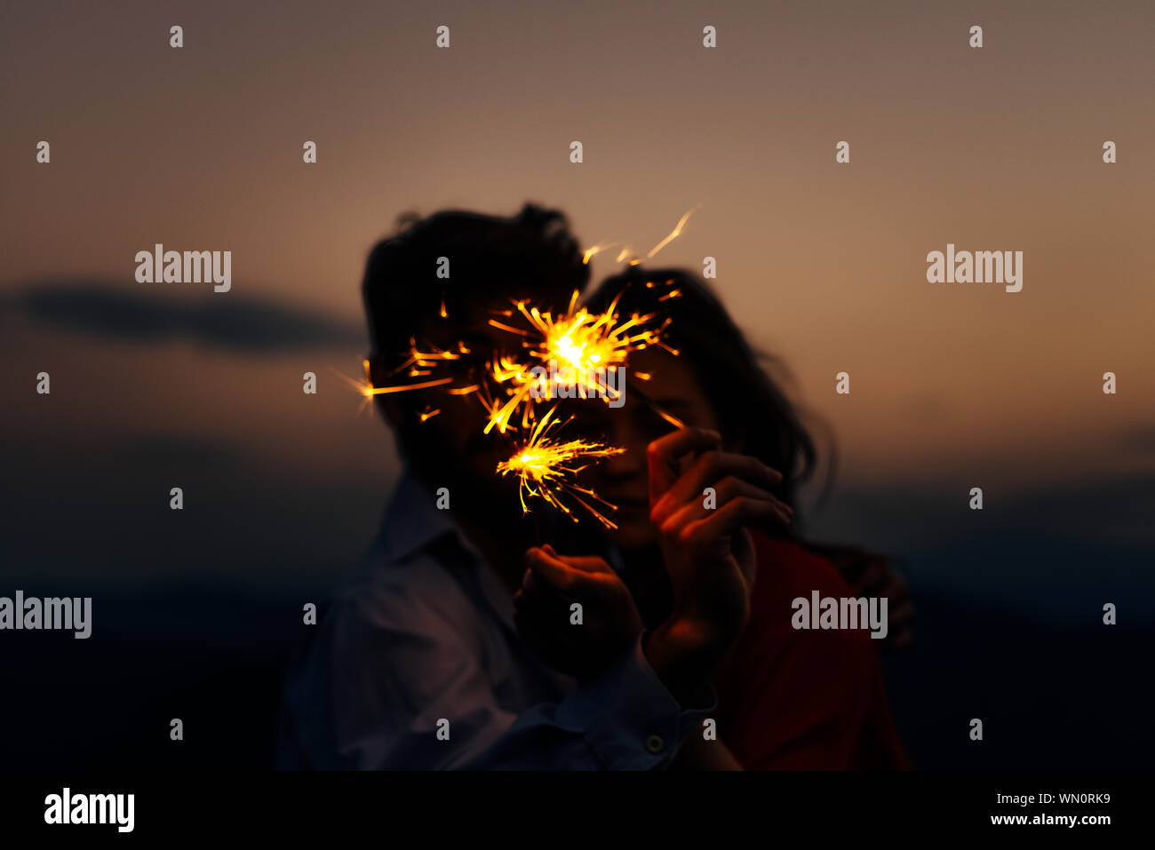 Portrait of young attractive celebrating couple holding firecrackers ...