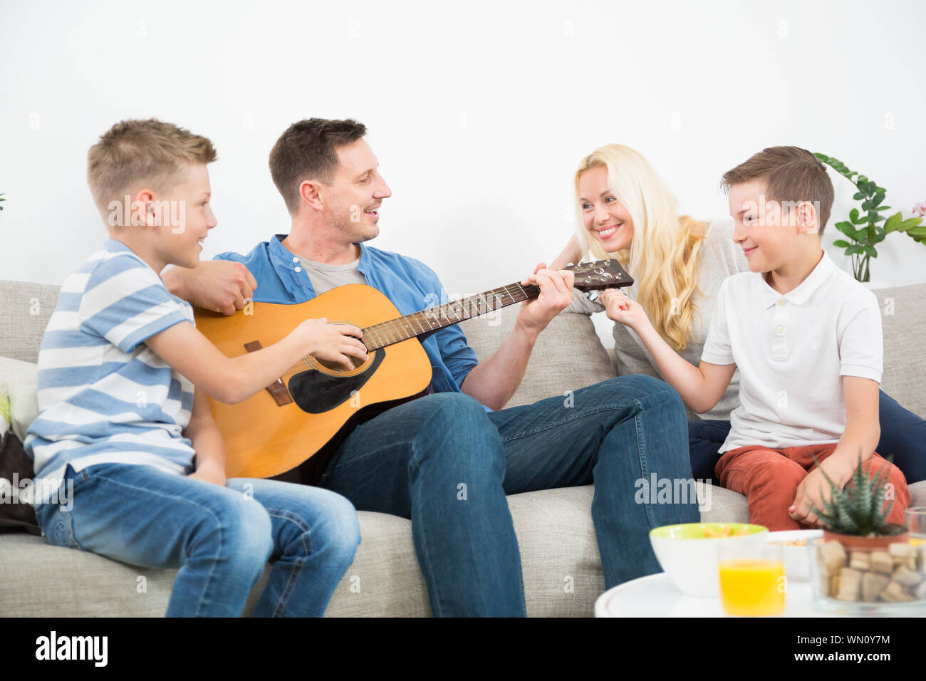 Happy caucasian family smiling, playing guitar and singing songs ...