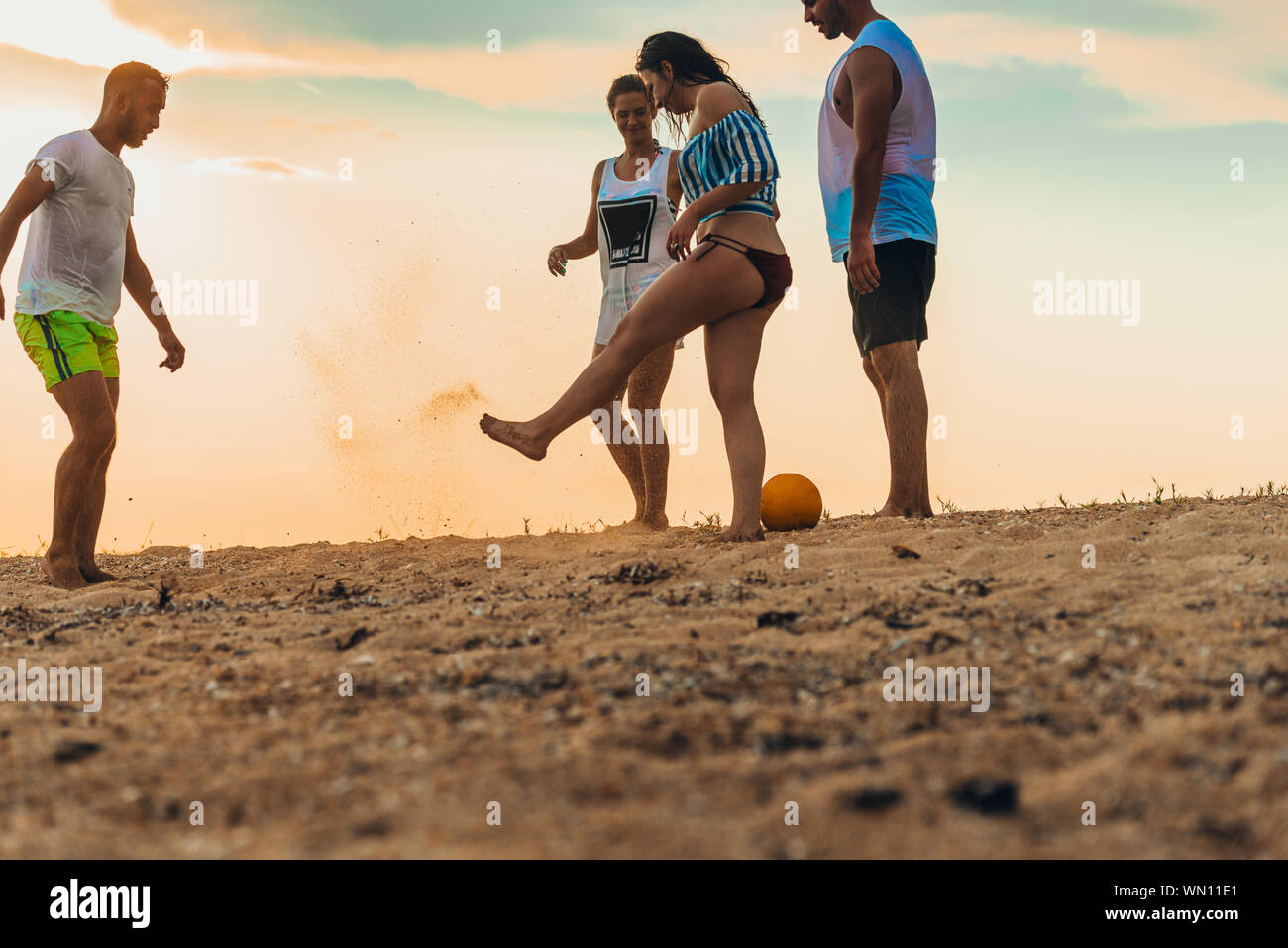 Friends playing football on the beach. concept sun, summer, sport and ...
