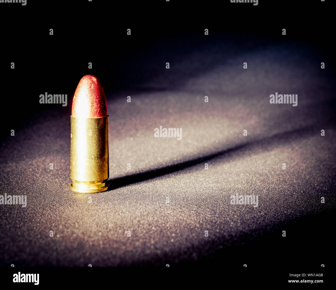 A single standing 9mm bullet with dramatic side light and shadows Stock ...