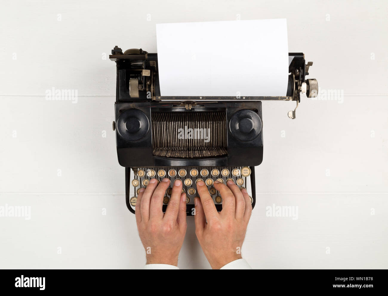 Man typing on vintage retro typewriter on white wooden table background ...