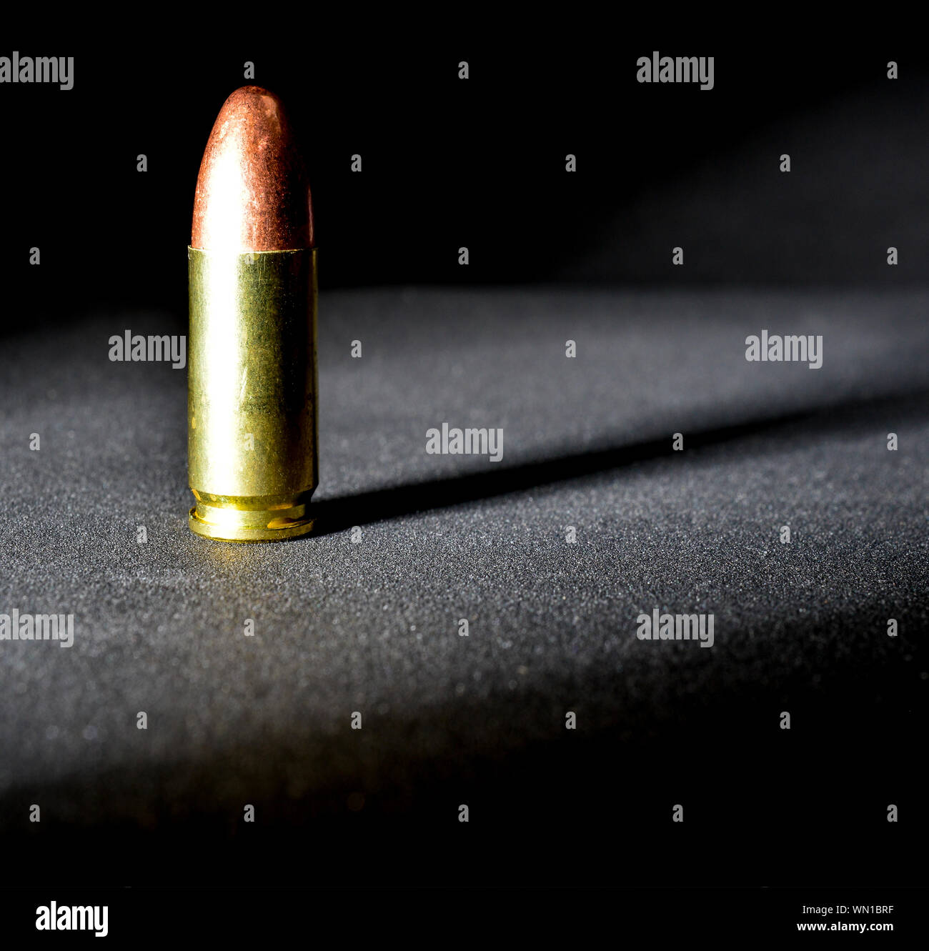A single standing 9mm bullet with dramatic side light and shadows Stock ...