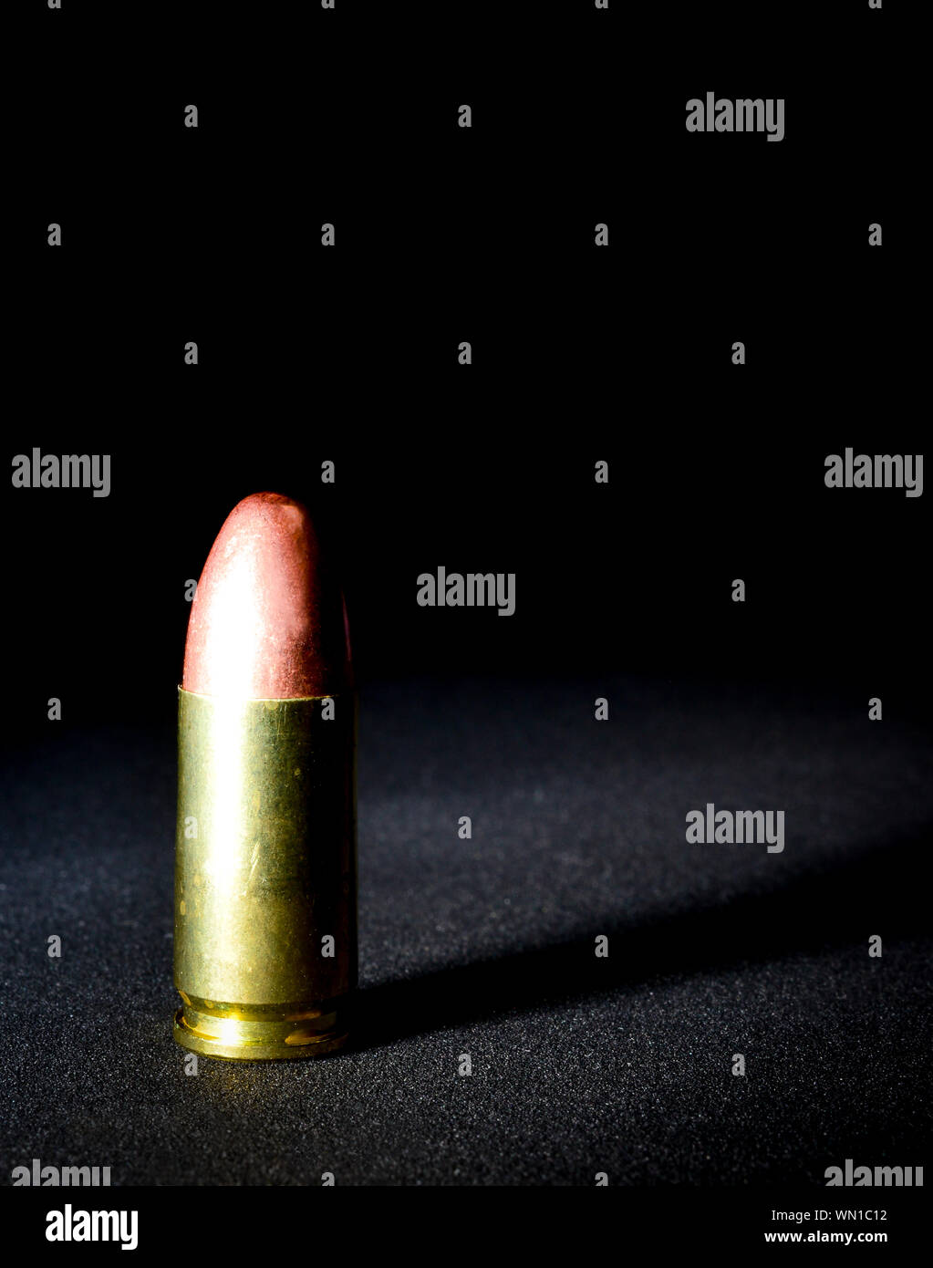 A single standing 9mm bullet with dramatic side light and shadows Stock ...
