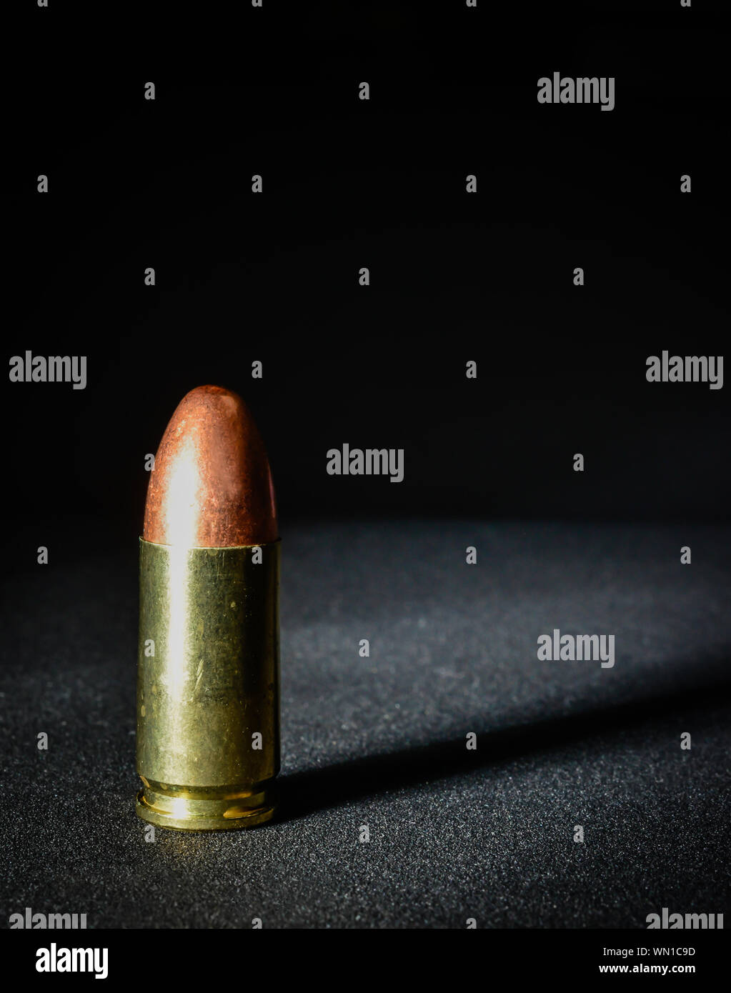 A single standing 9mm bullet with dramatic side light and shadows Stock ...