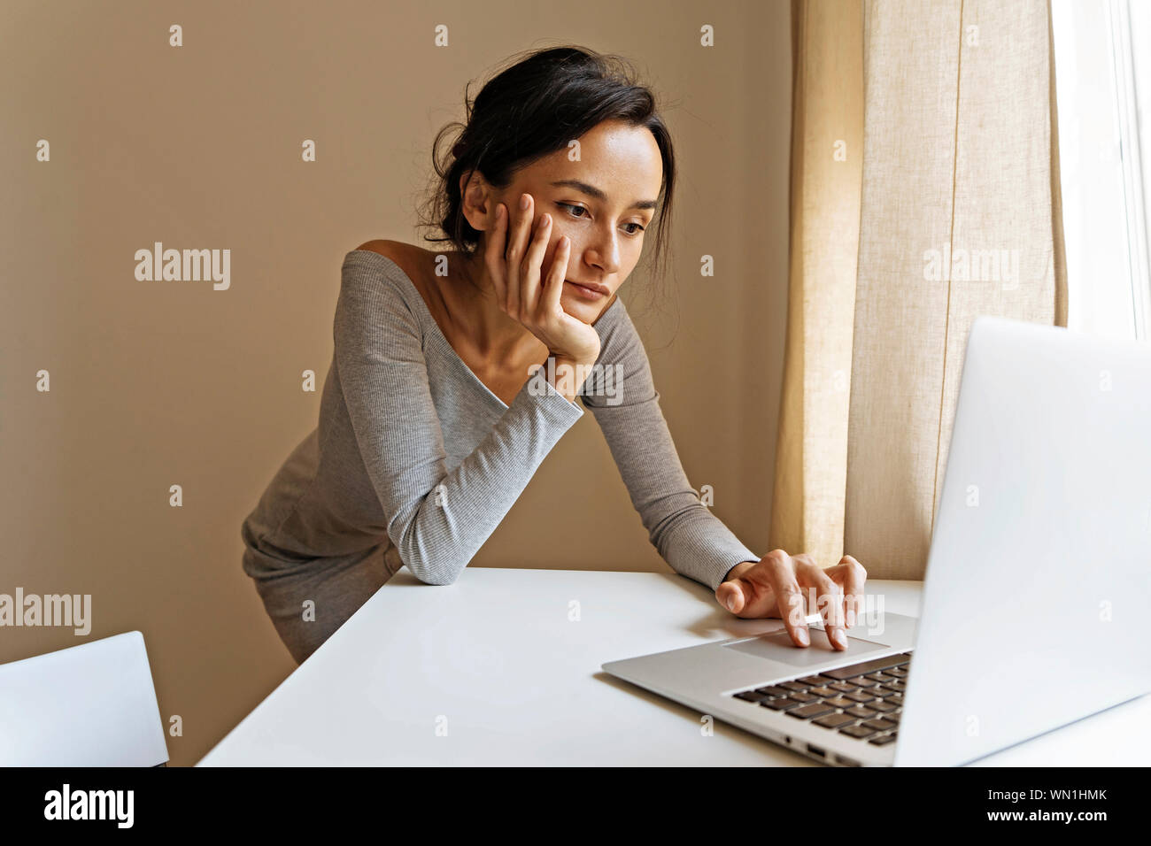 Woman leaning on table using laptop Stock Photo - Alamy