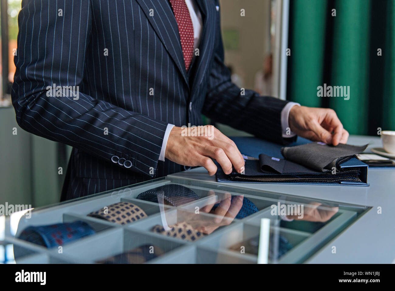 Shop assistant wearing pinstripe suit holding swatches Stock Photo - Alamy