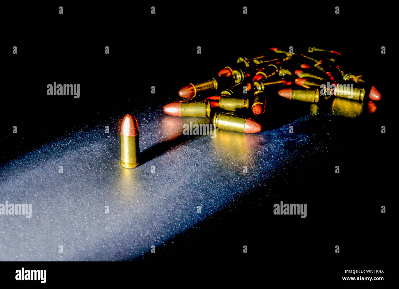 A single 9mm bullet stands alone with strong side light creating ...