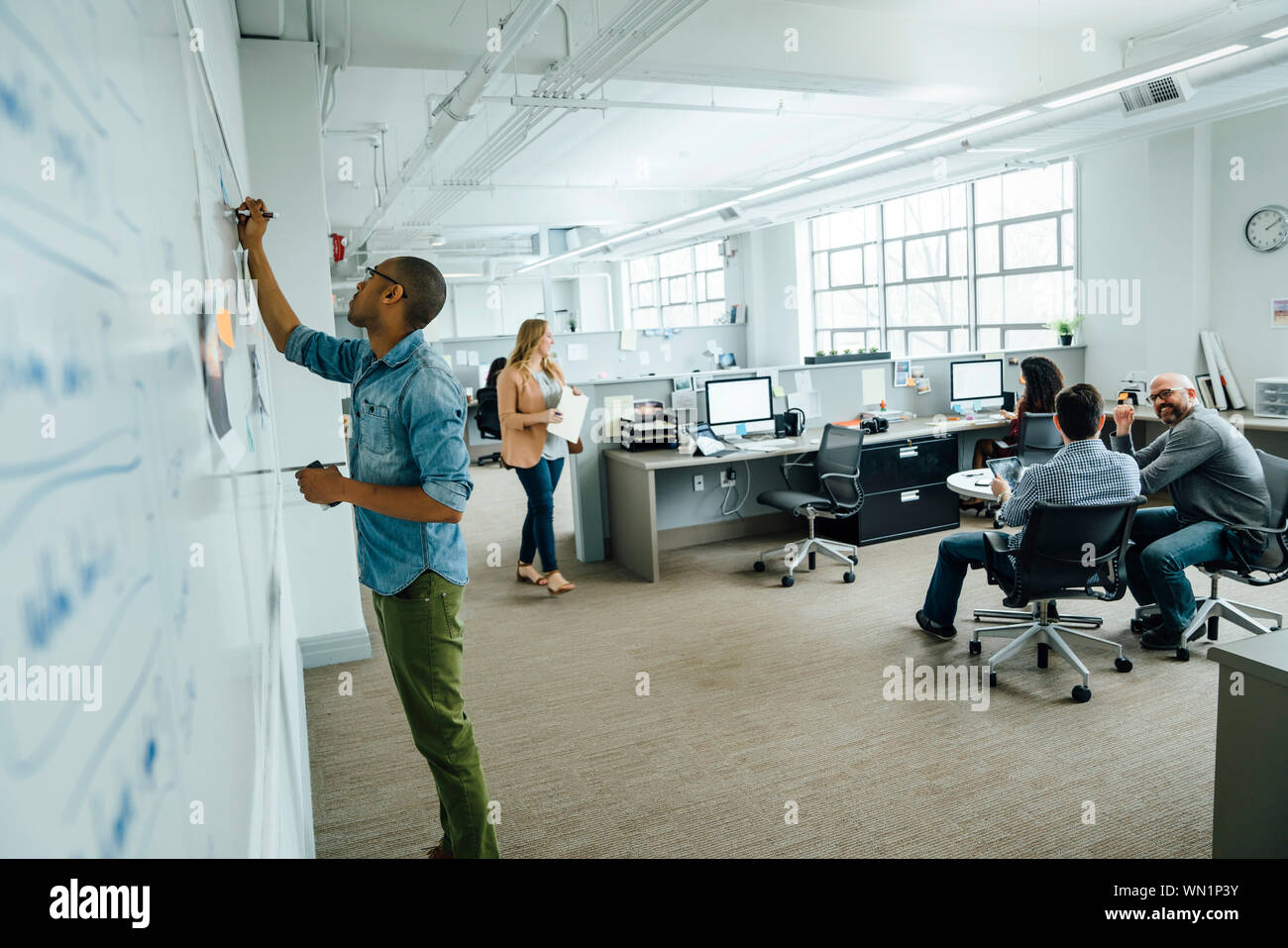 Man writing on whiteboard in office Stock Photo - Alamy
