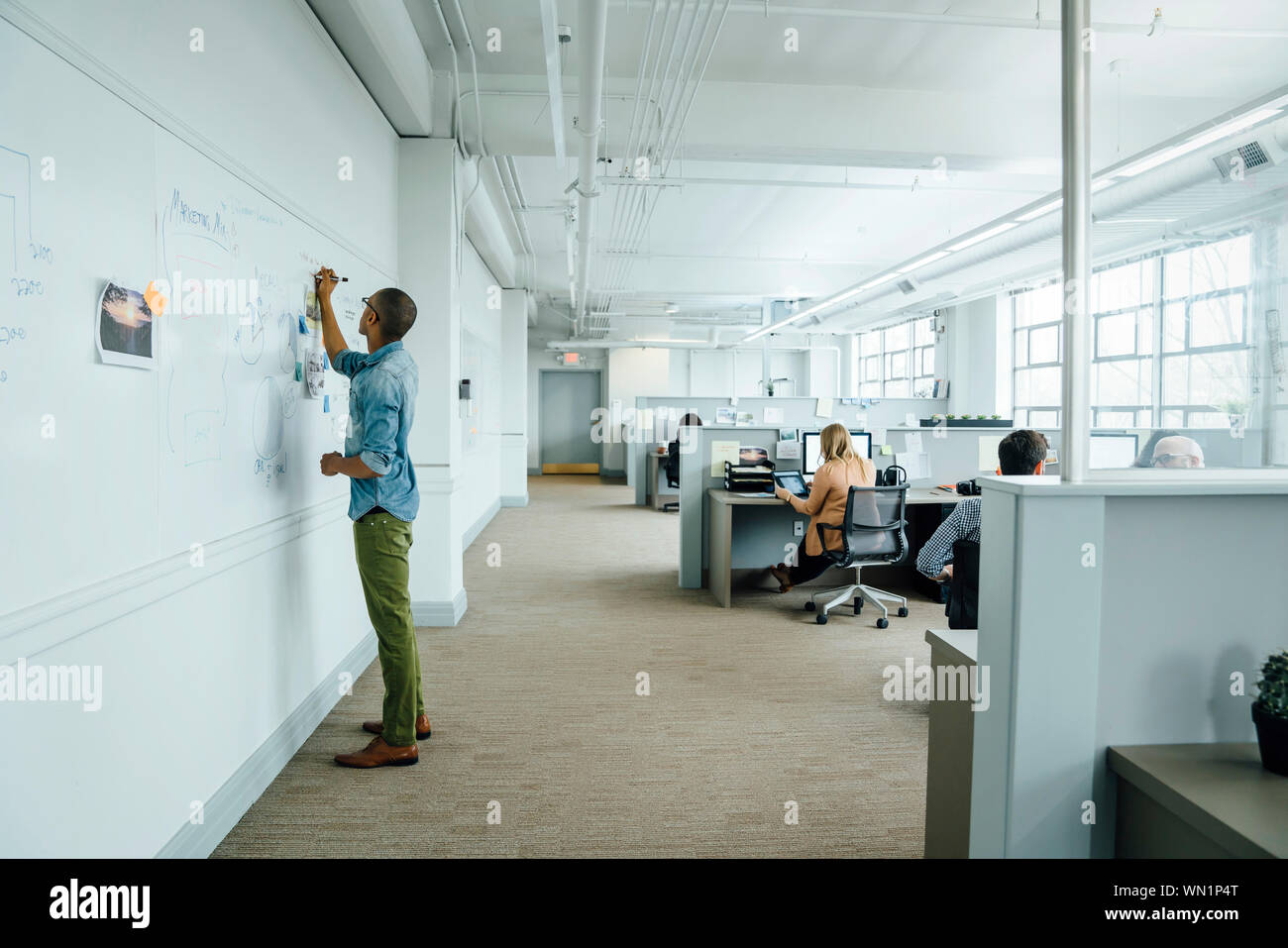 Man writing on whiteboard in office Stock Photo - Alamy