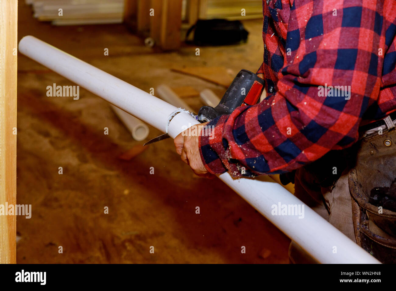Plumber cutting PVC pipe in the house construction using a jigsaw Stock ...