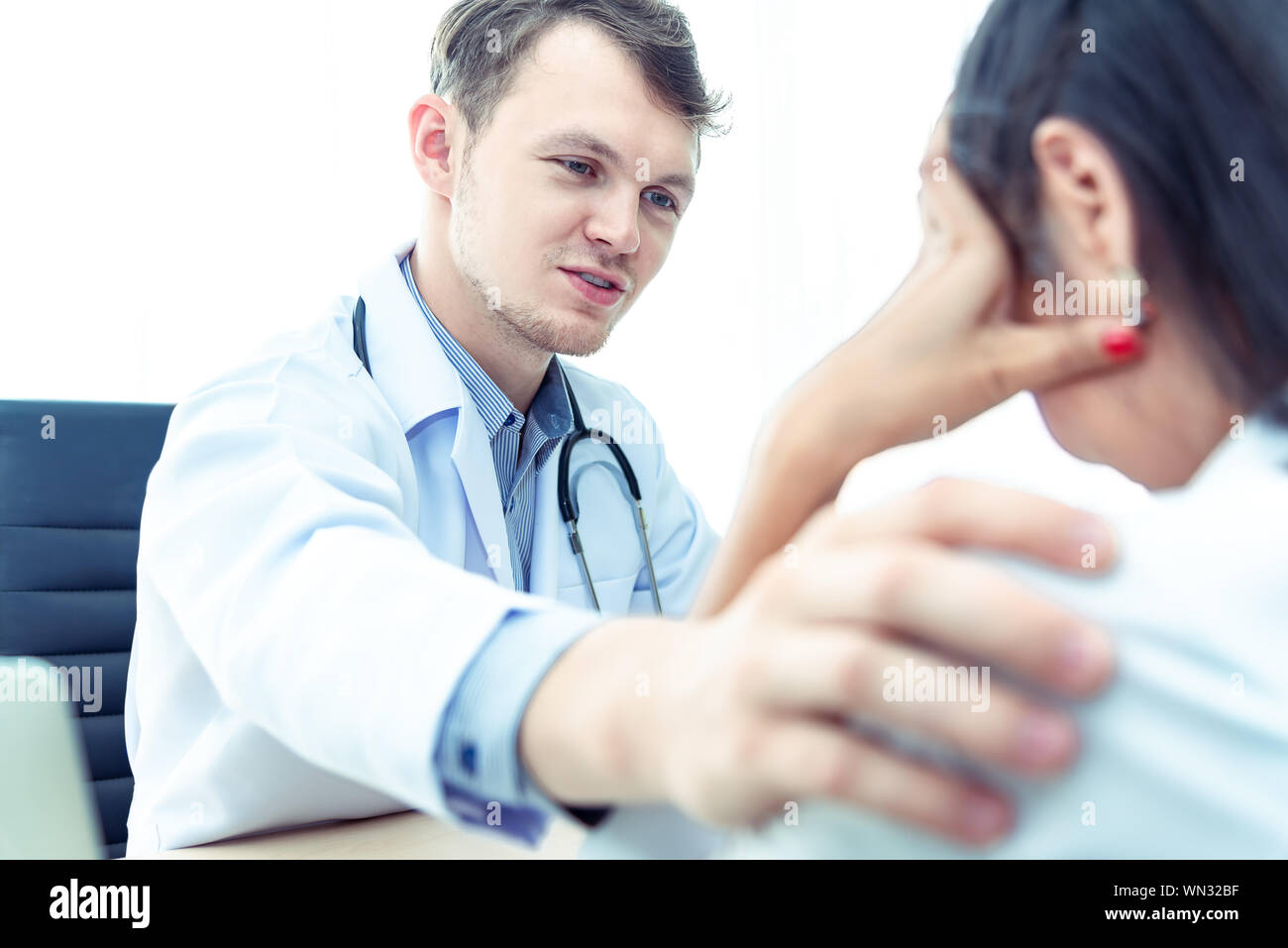 Professional doctor man with stethoscope reassuring woman patient on ...