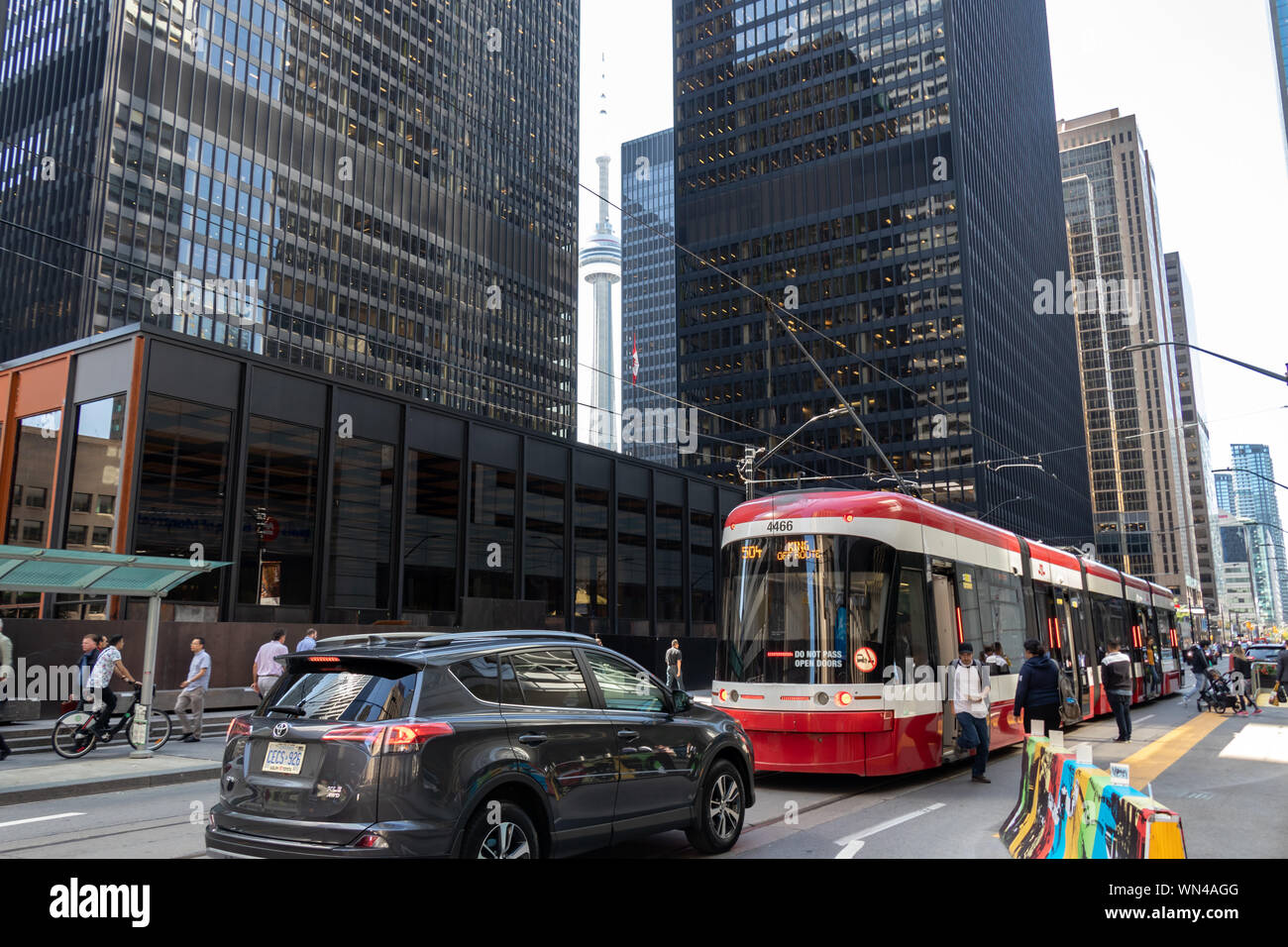TTC streetcar unloading passengers in financial district with CN Tower ...