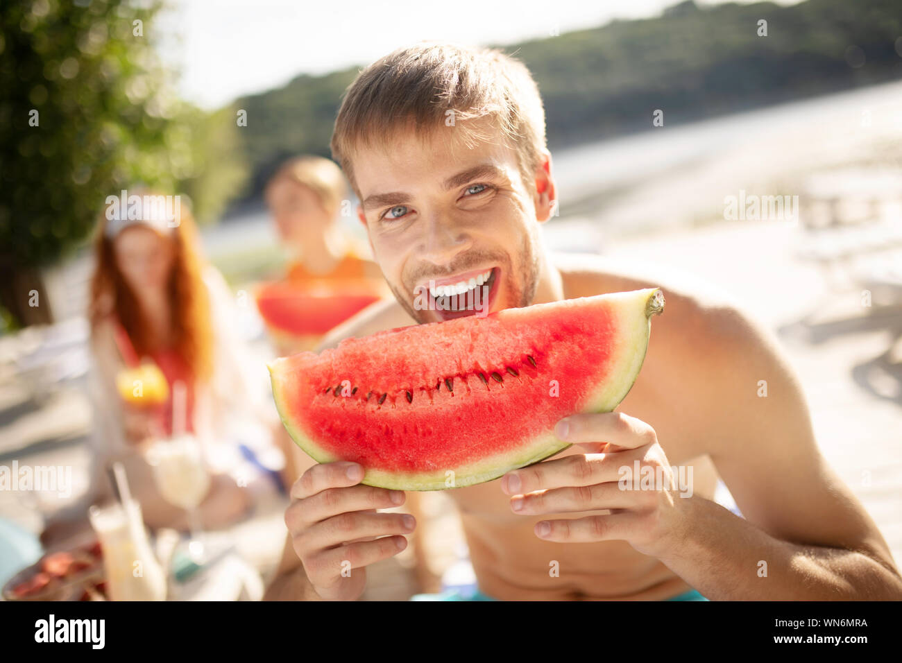 Handsome man laughing while biting watermelon Stock Photo - Alamy