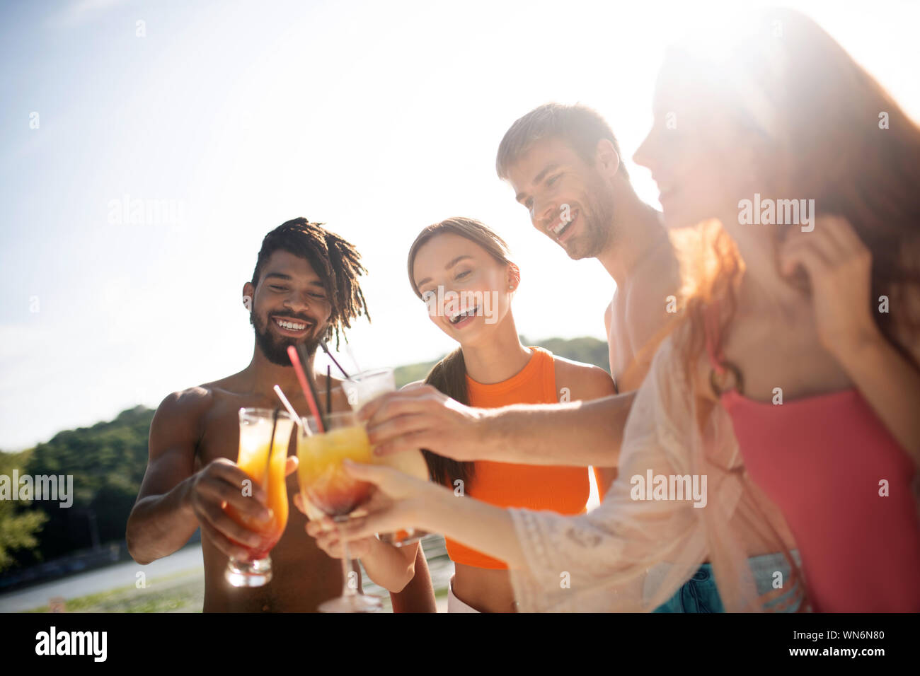 Cheerful millennials laughing while drinking summer cocktails Stock ...