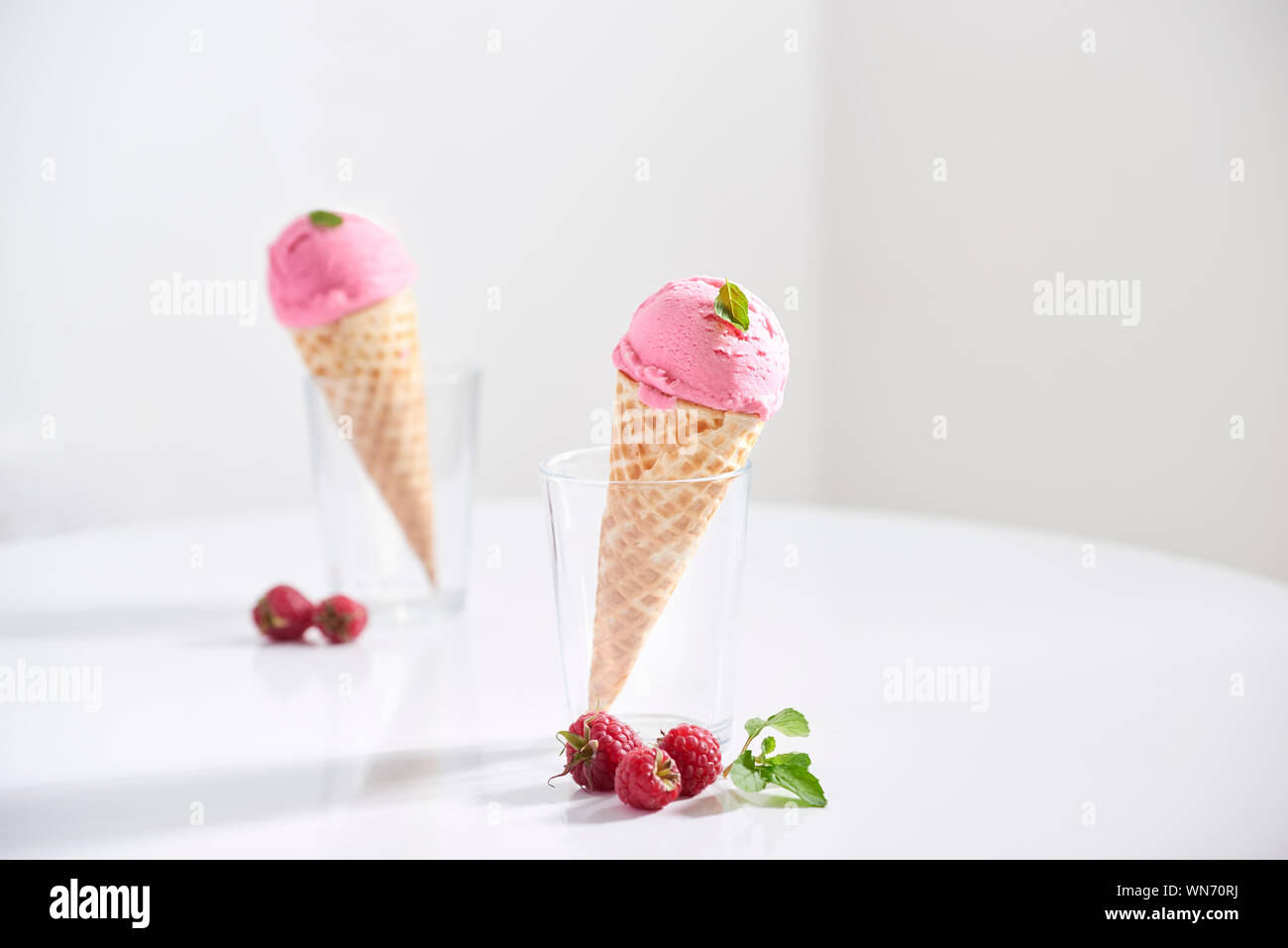 Waffle cone filled with fresh raspberry ice cream in glass cup with ...