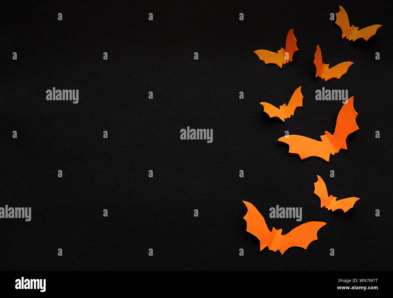 halloween concept - orange paper bats flying over black background ...