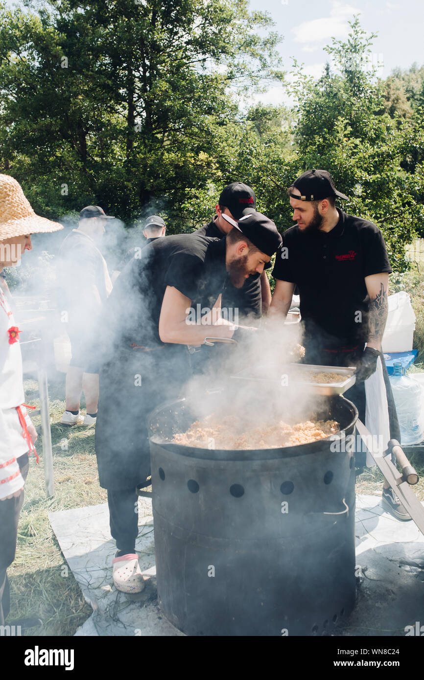 Men putting pilaf from cauldron into container Stock Photo - Alamy