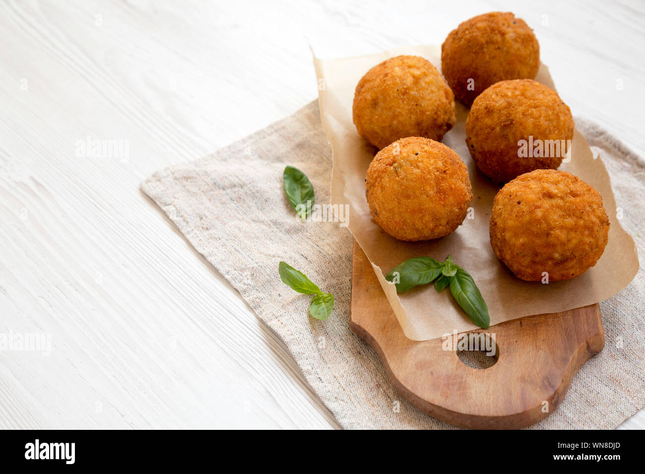 Homemade fried Arancini with basil on a rustic wooden board, side view ...