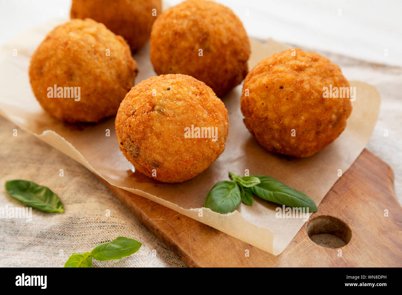 Homemade fried Arancini with basil on a rustic wooden board, side view ...