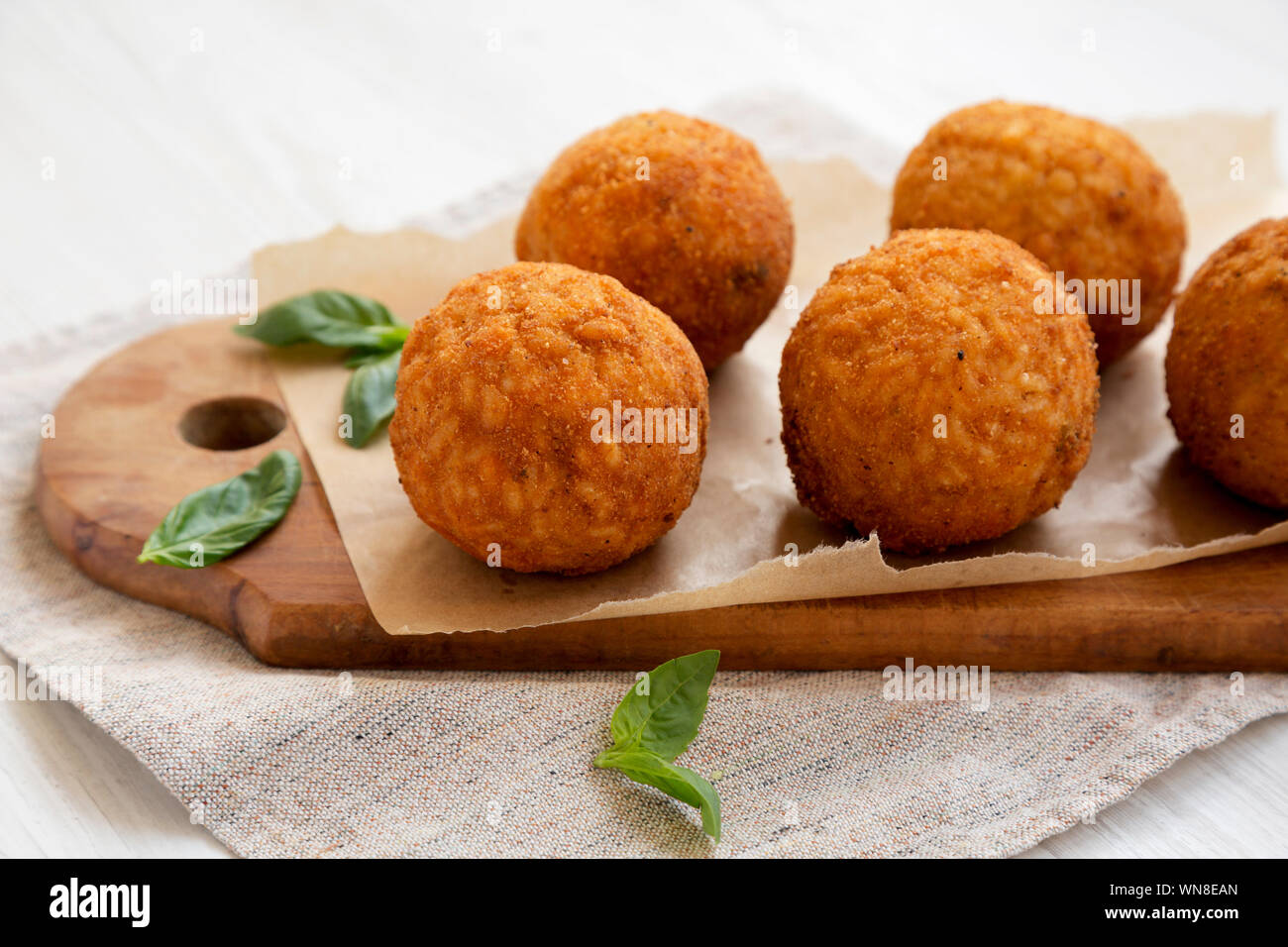 Homemade fried Arancini with basil on a white wooden background, side ...