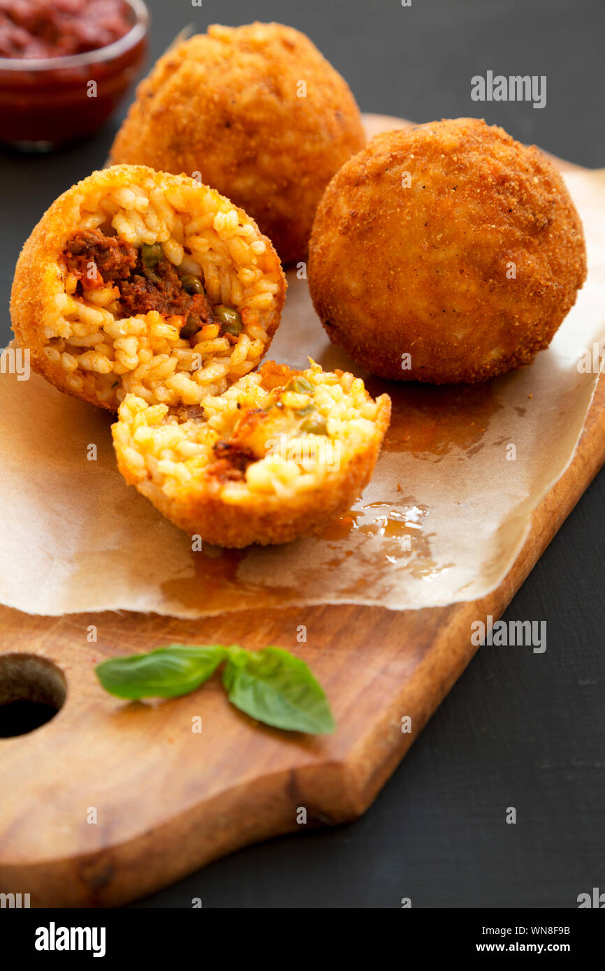 Homemade fried Arancini with basil and Marinara sauce on a black ...