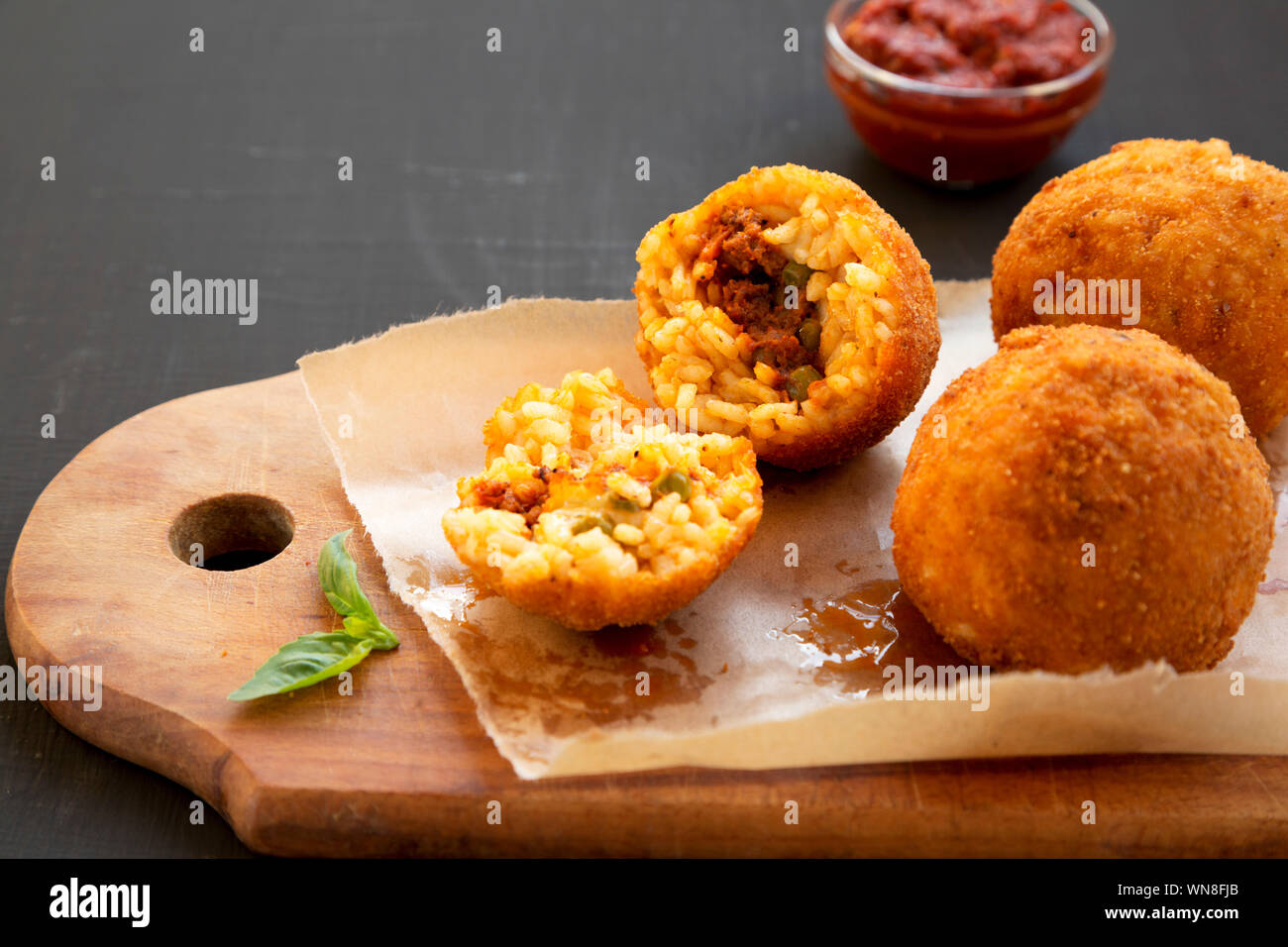 Homemade fried Arancini with basil and Marinara sauce on a black ...
