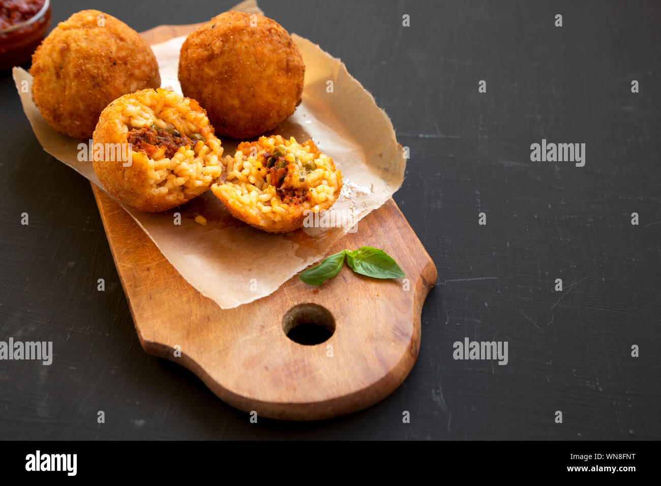 Homemade fried Arancini with basil and Marinara on a black background ...
