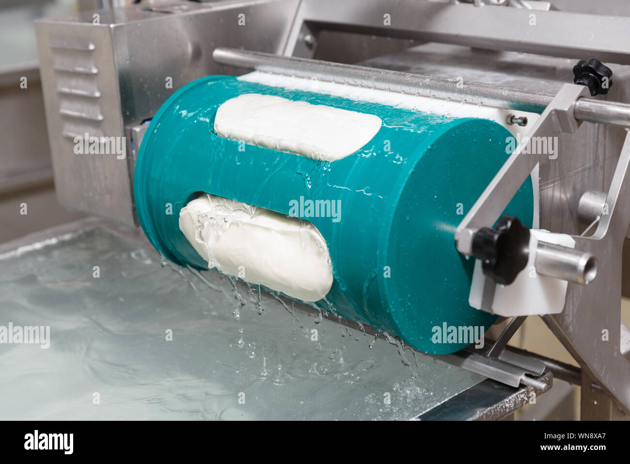 Fresh and hot mozzarella cheese put in a form before cooling bath on a ...