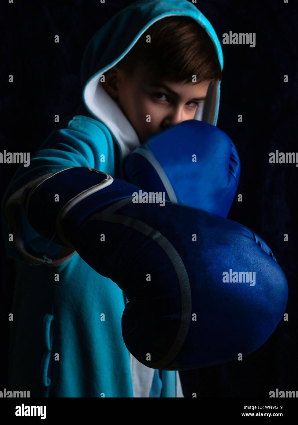 Aggressive child wearing boxing gloves, low-key lighting Stock Photo ...