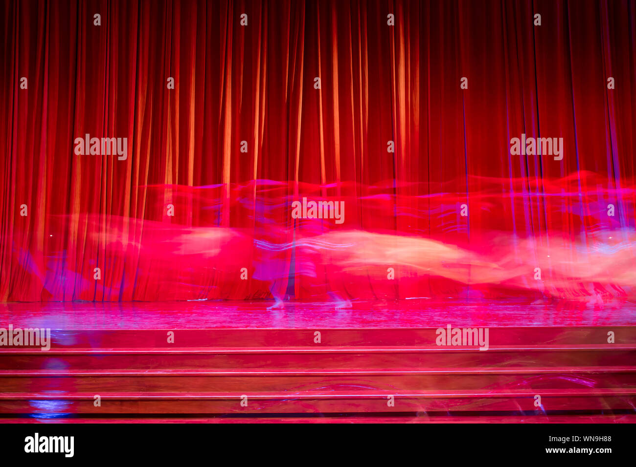 Red curtains and movements of the performers on stage in a theater ...