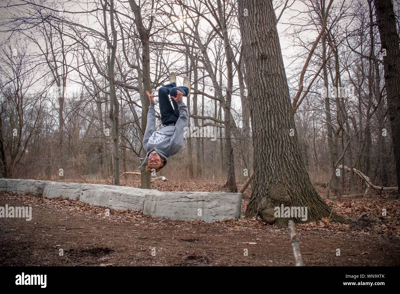 Young Man Backflipping On Field At Forest Stock Photo - Alamy