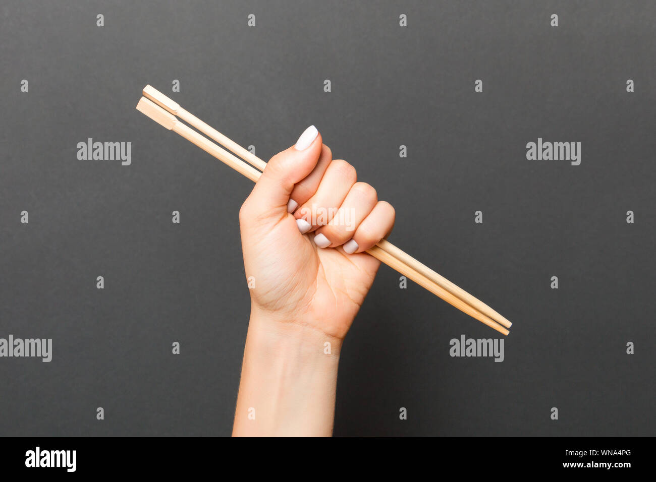 Woman's hand holding chopsticks on black background. Chinese food ...