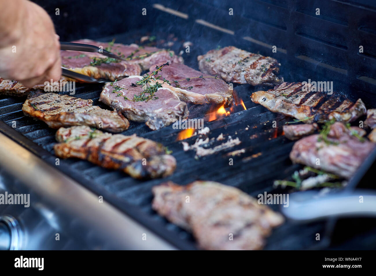 Chef grilling beef steak on a barbecue at the outdoor garden party ...