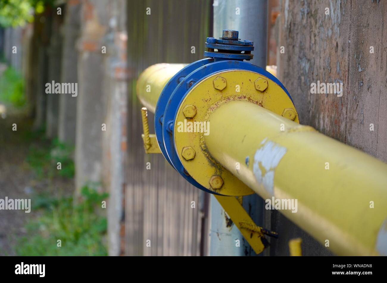 Yellow gas pipe in front of residential building wall. Stone wall ...