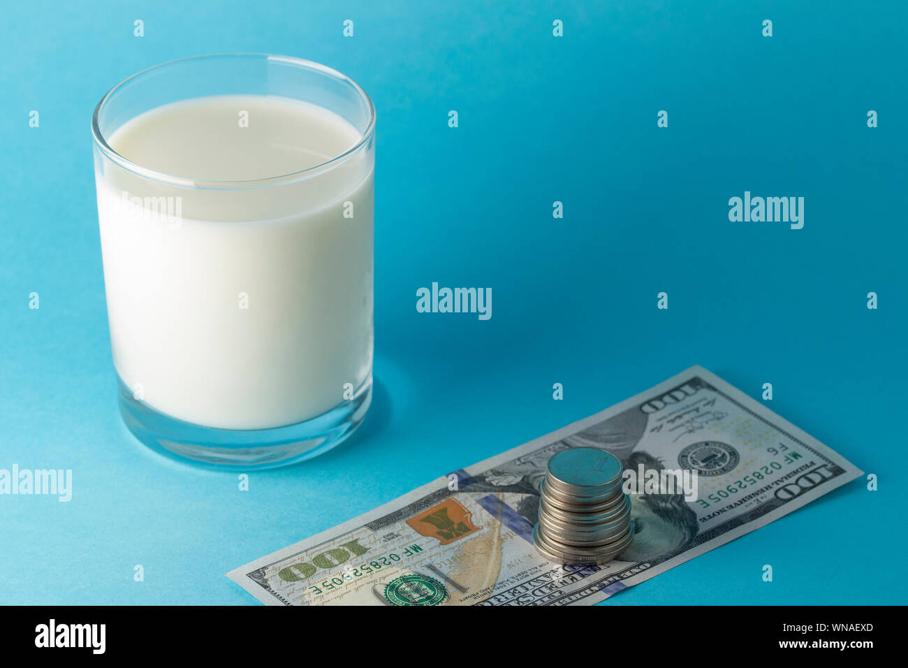 Glass milk on a blue background with cash. price increase for dairy ...