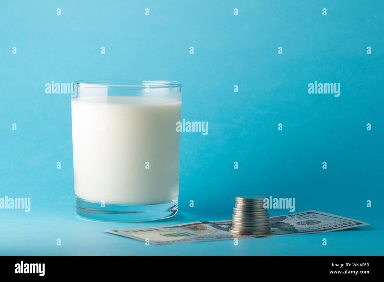 Glass milk on a blue background with cash. price increase for dairy ...