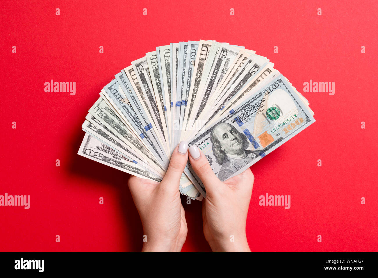 Top view of female hand holding a fan of money on colorful background ...