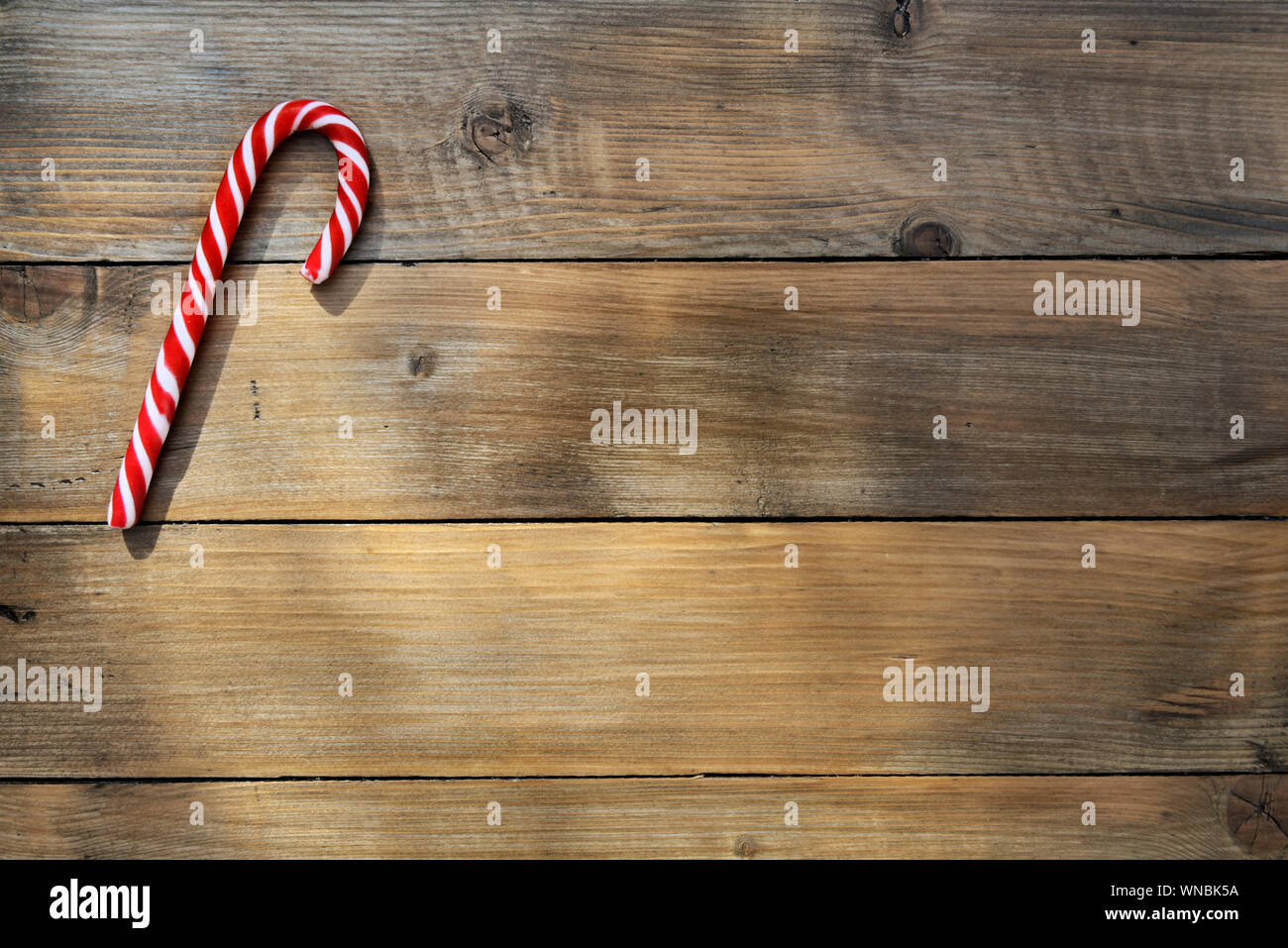 single red candy cane on a brown rustic plank Stock Photo - Alamy