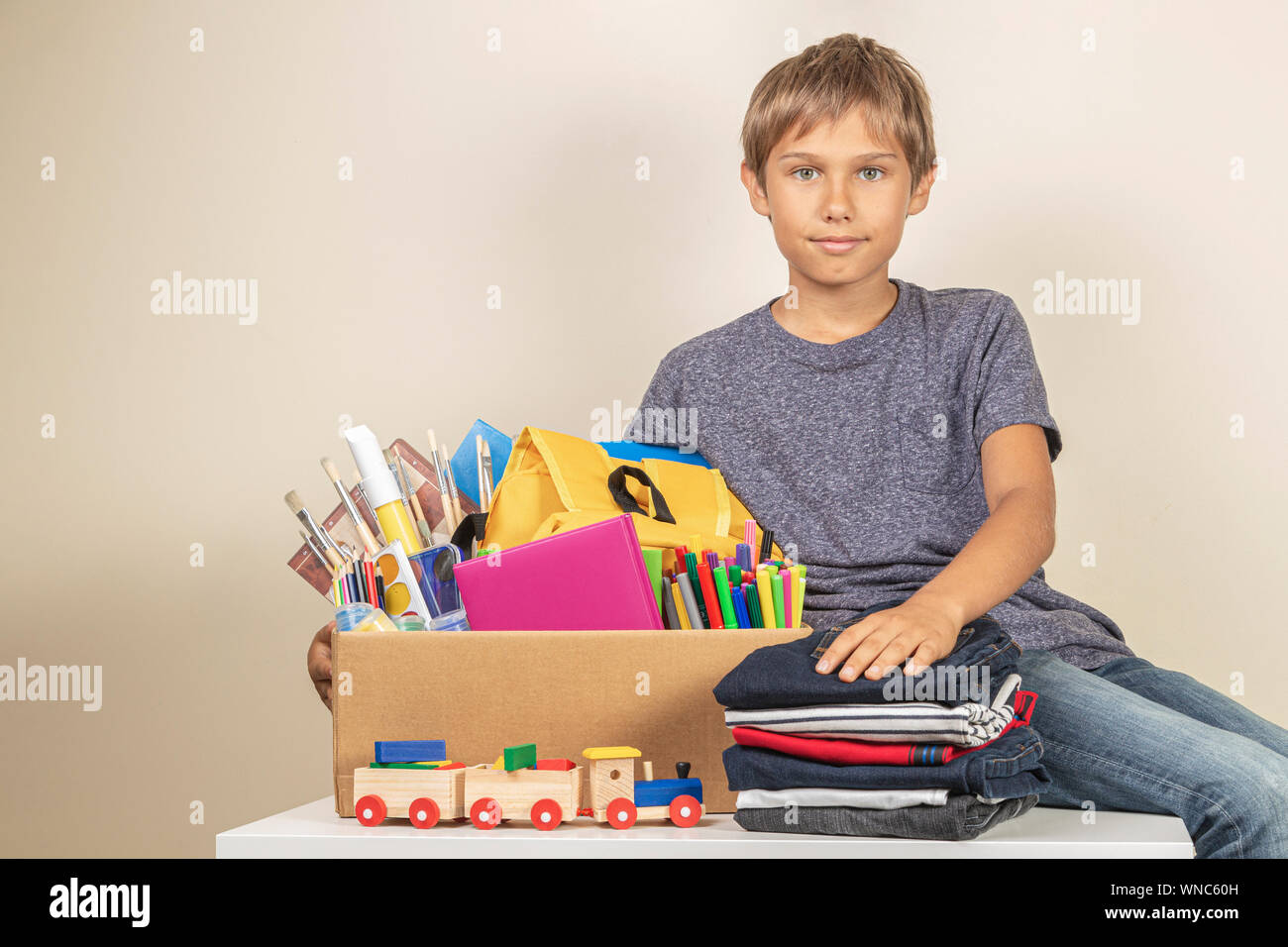 Donation concept. Kid holding donate box with books, pencils and school ...